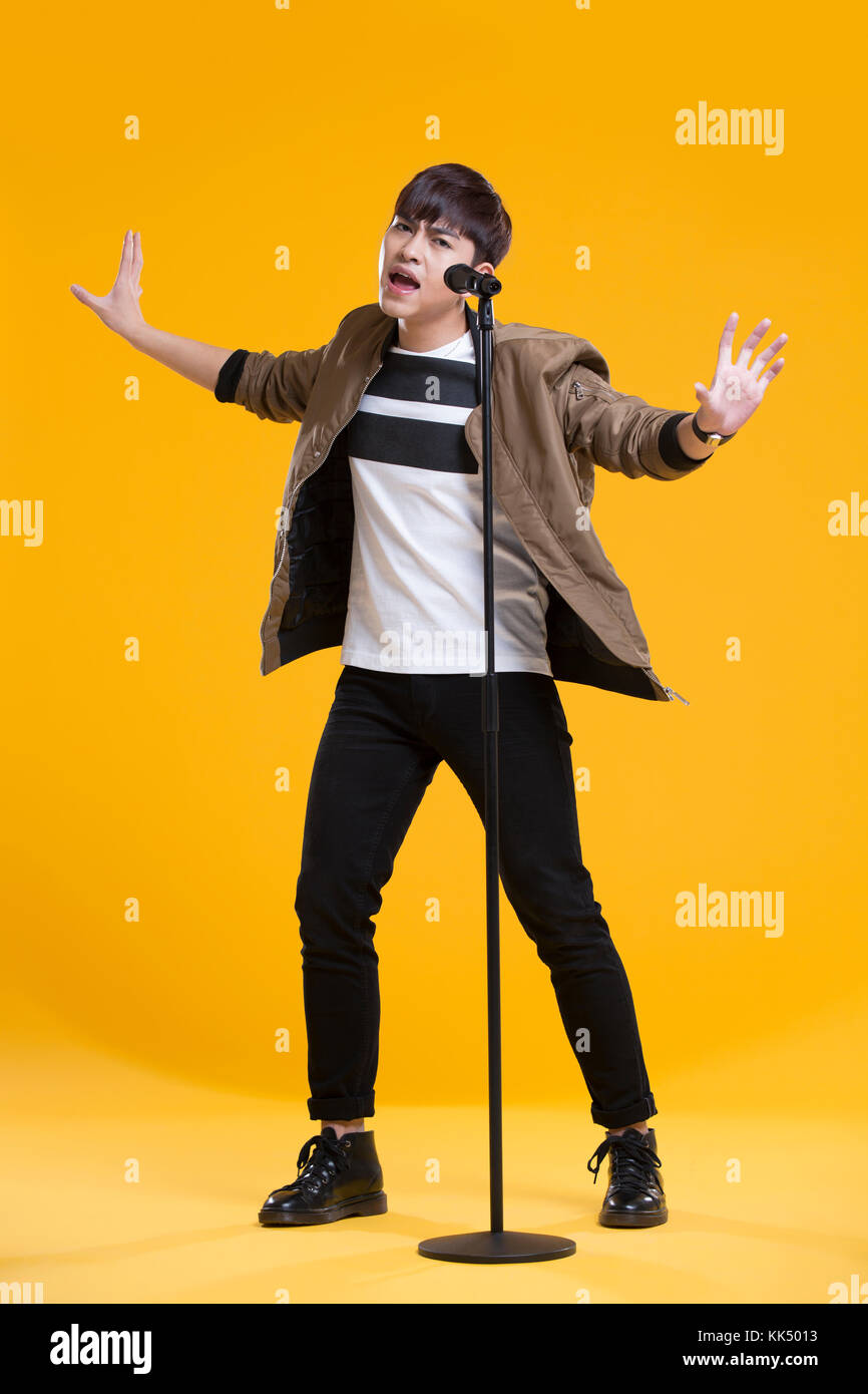 Cheerful young Chinese man singing with microphone Stock Photo - Alamy