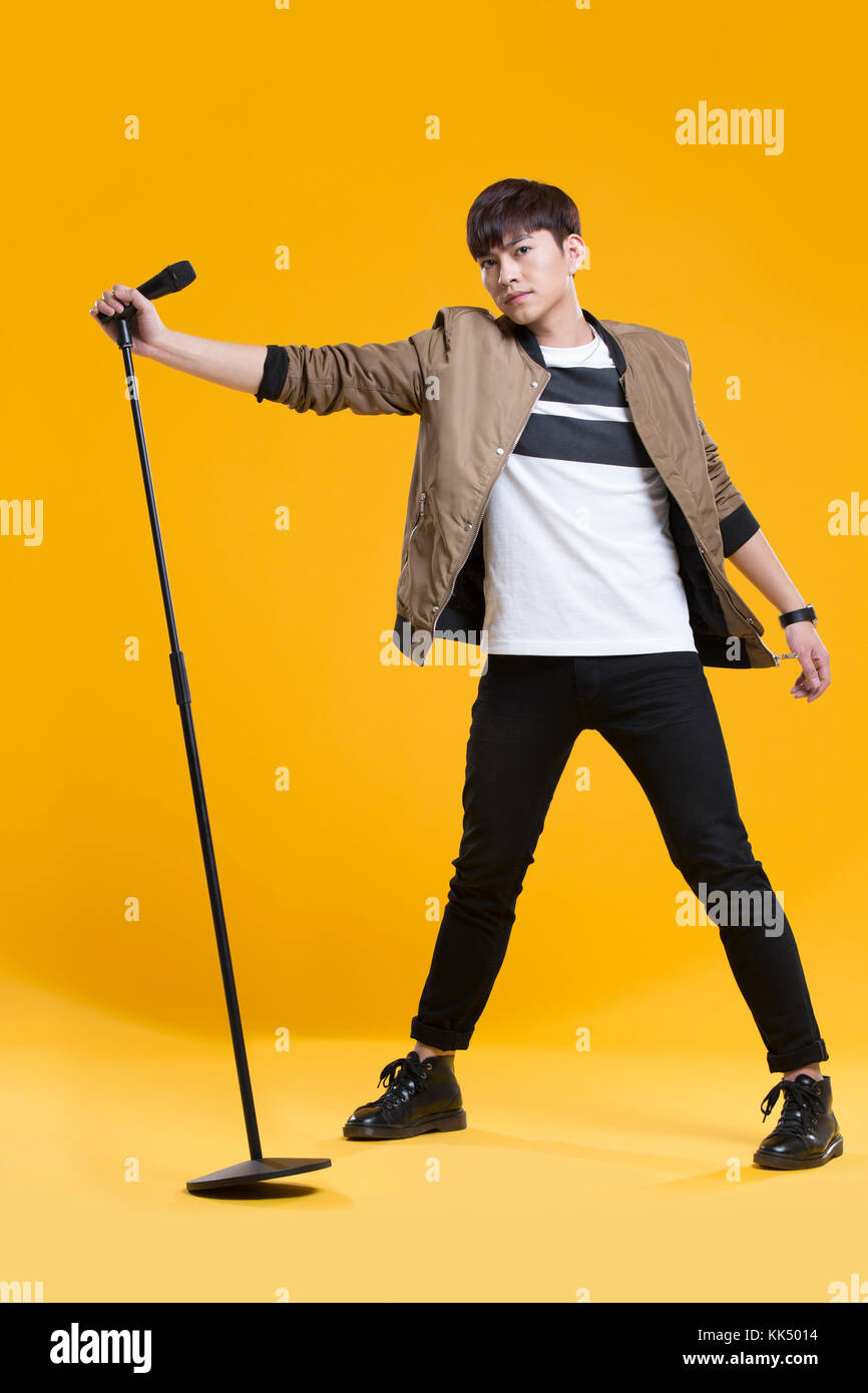 Cheerful young Chinese man singing with microphone Stock Photo - Alamy