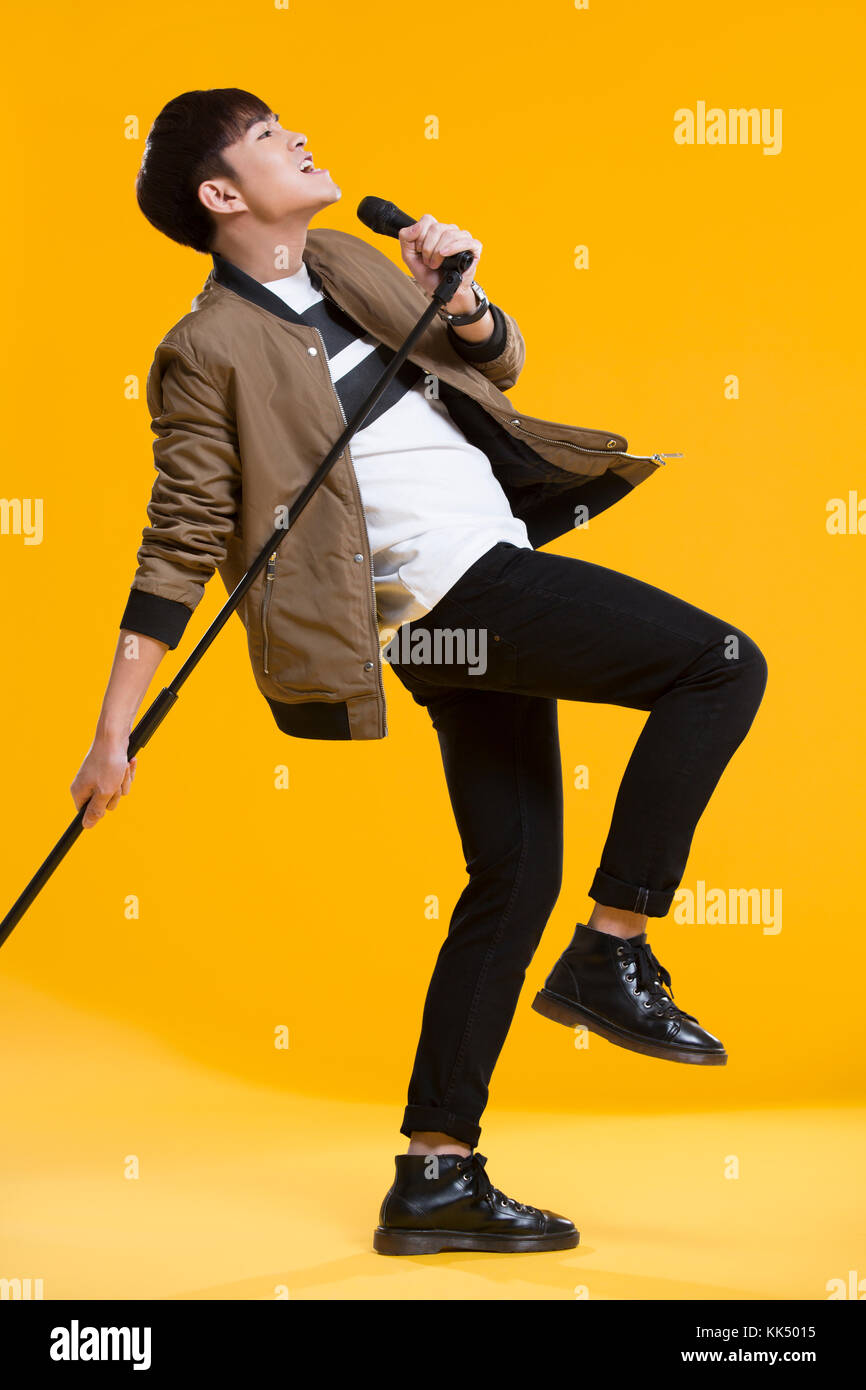 Cheerful young Chinese man singing with microphone Stock Photo - Alamy