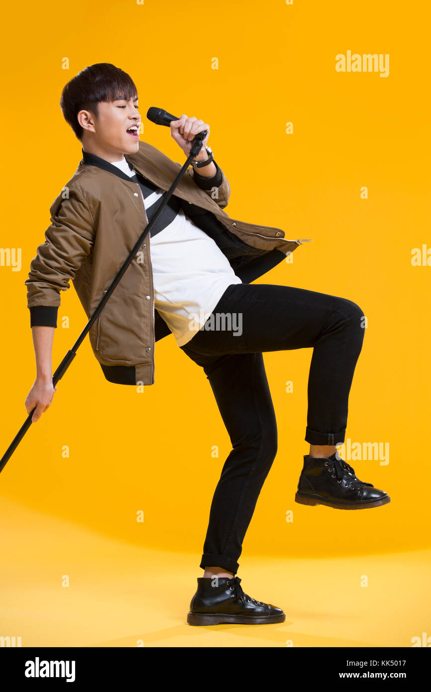 Cheerful young Chinese man singing with microphone Stock Photo - Alamy