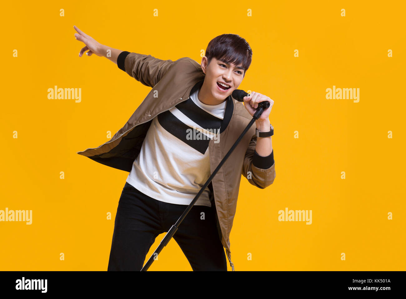 Cheerful young Chinese man singing with microphone Stock Photo - Alamy