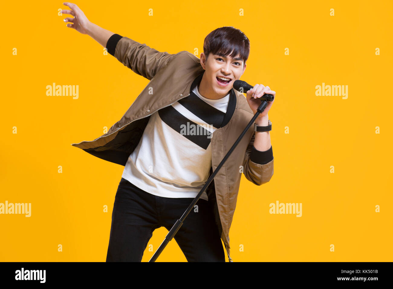 Cheerful young Chinese man singing with microphone Stock Photo - Alamy