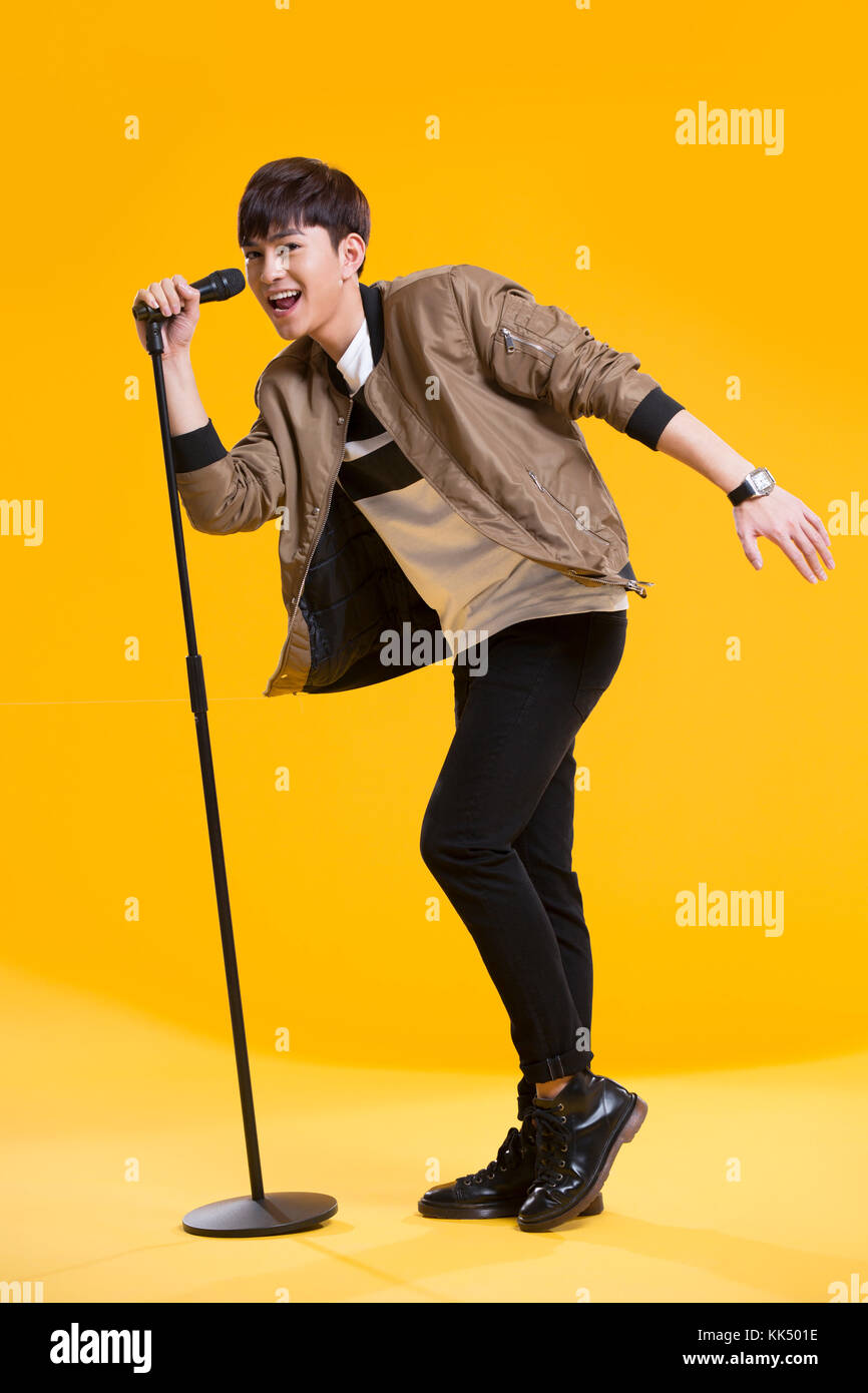 Cheerful young Chinese man singing with microphone Stock Photo - Alamy