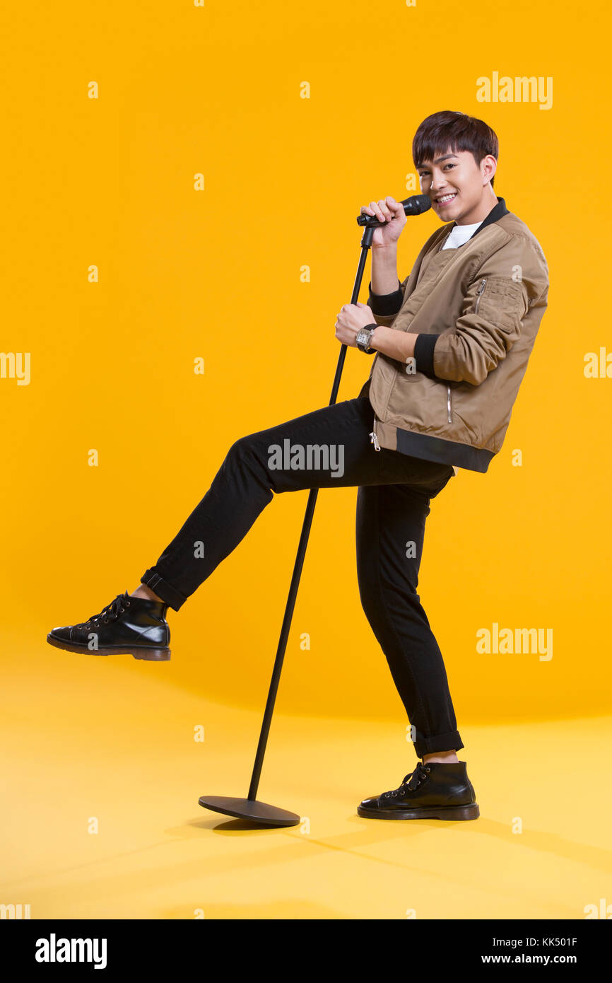 Cheerful young Chinese man singing with microphone Stock Photo - Alamy