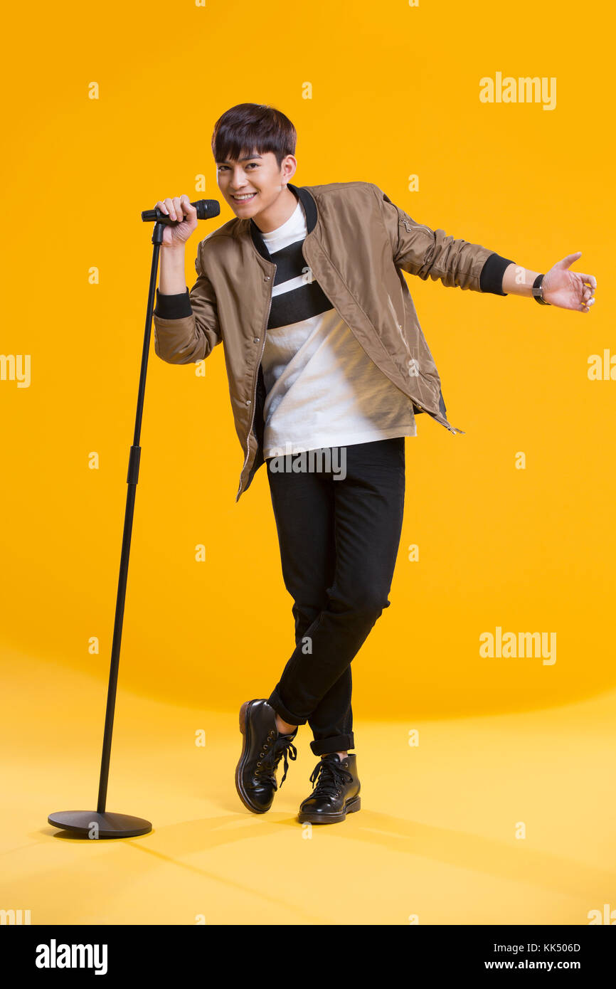 Cheerful young Chinese man singing with microphone Stock Photo - Alamy