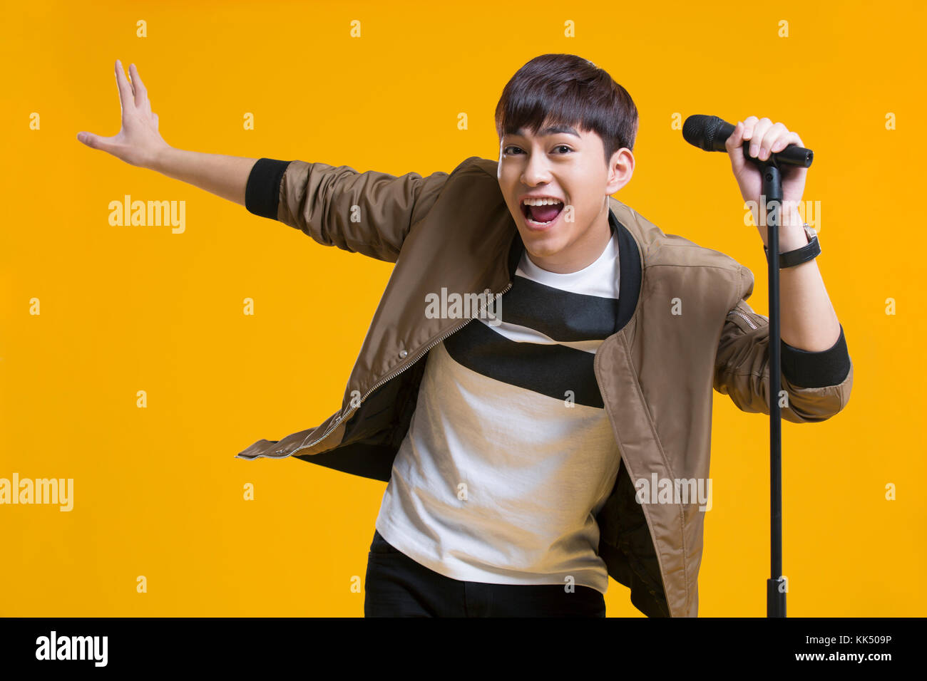 Cheerful young Chinese man singing with microphone Stock Photo - Alamy