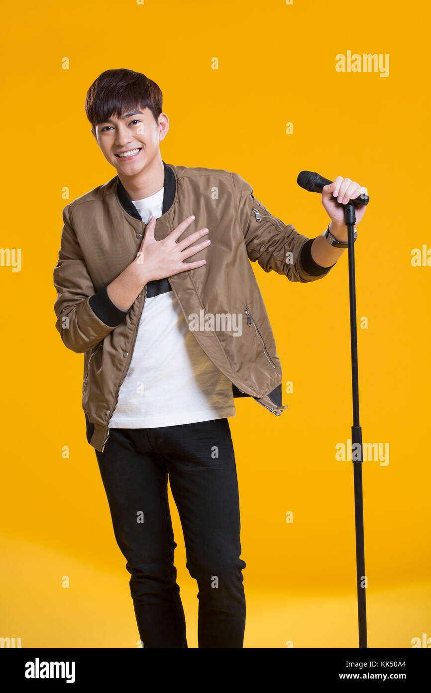 Cheerful young Chinese man singing with microphone Stock Photo - Alamy
