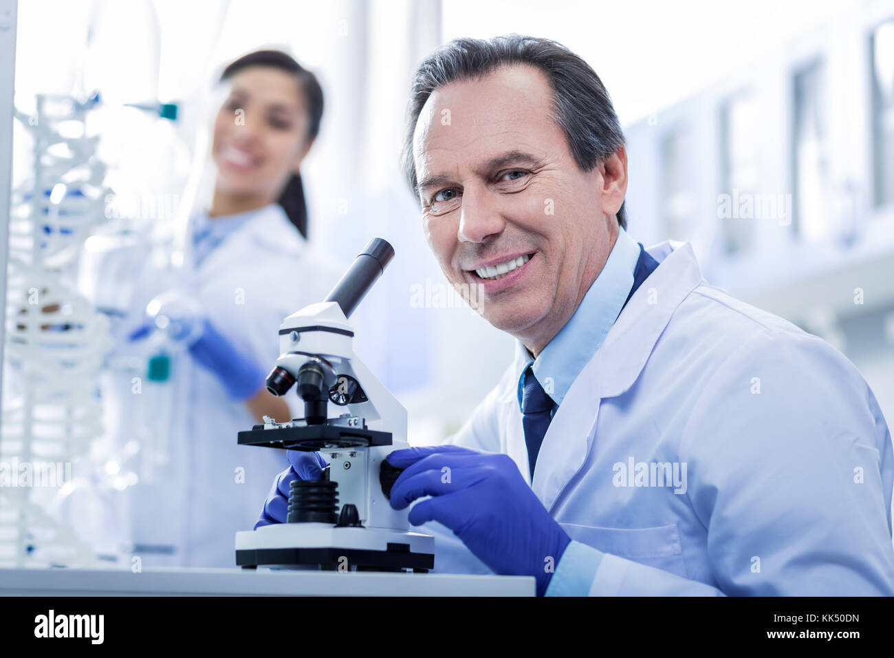 Nice happy man holding a microscope Stock Photo - Alamy
