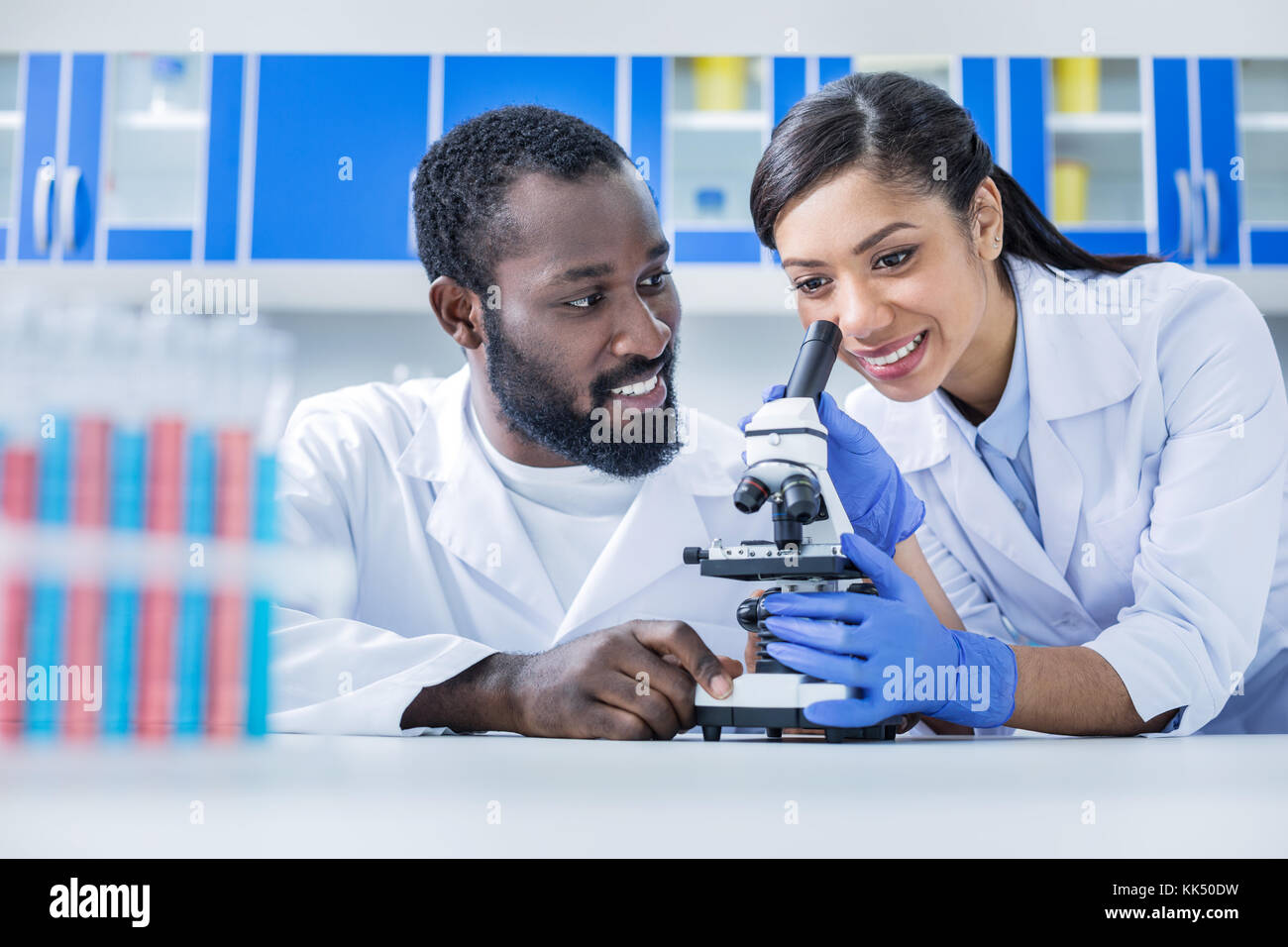 Delighted positive woman using a microscope Stock Photo - Alamy