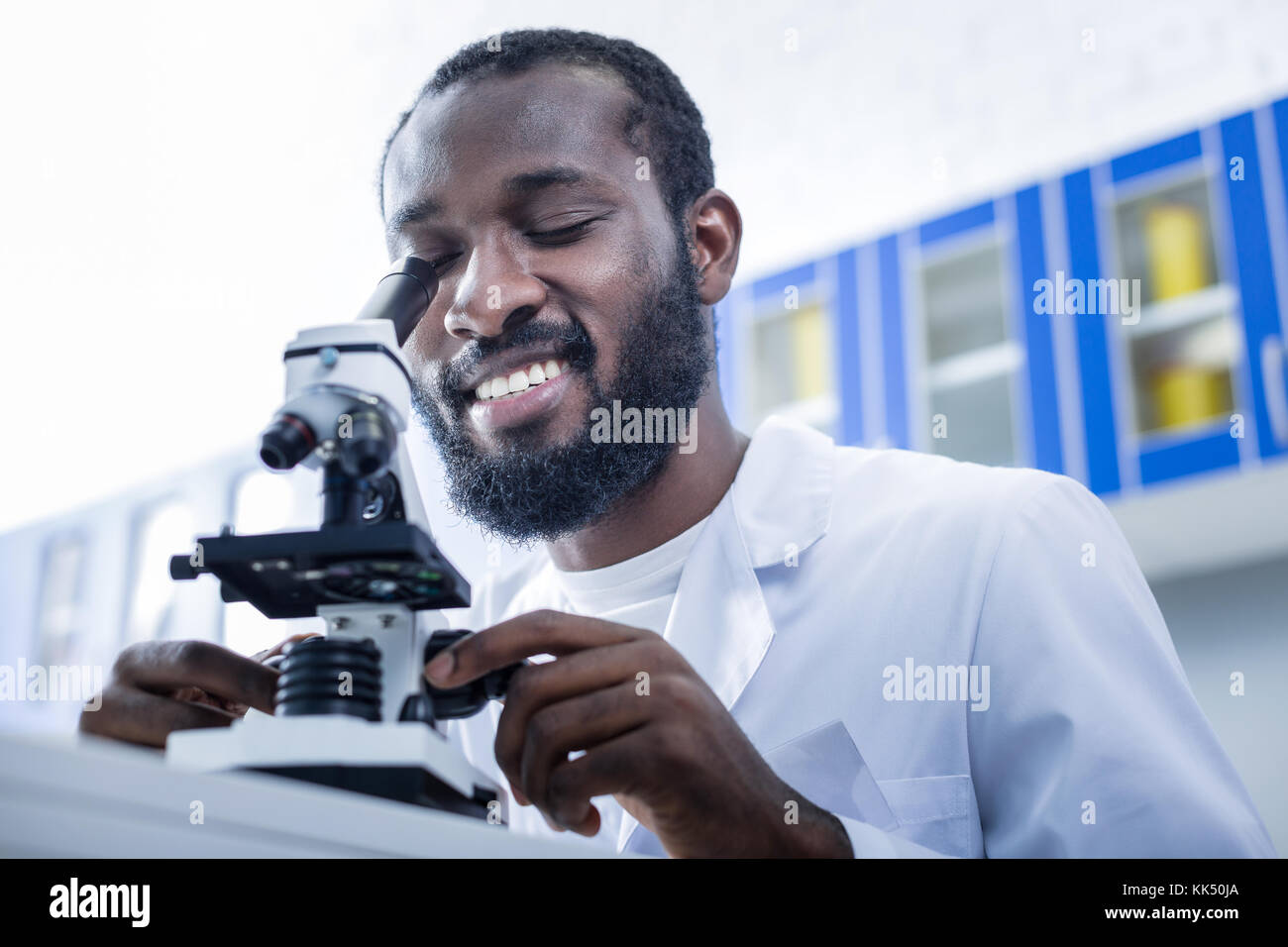 Happy positive man looking into the microscope Stock Photo - Alamy