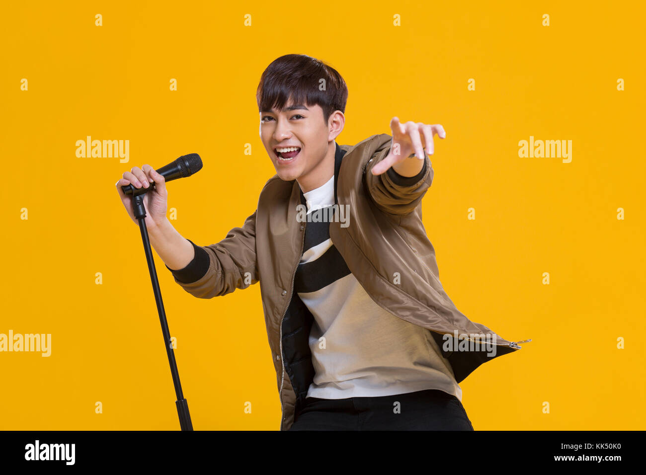 Cheerful young Chinese man singing with microphone Stock Photo - Alamy