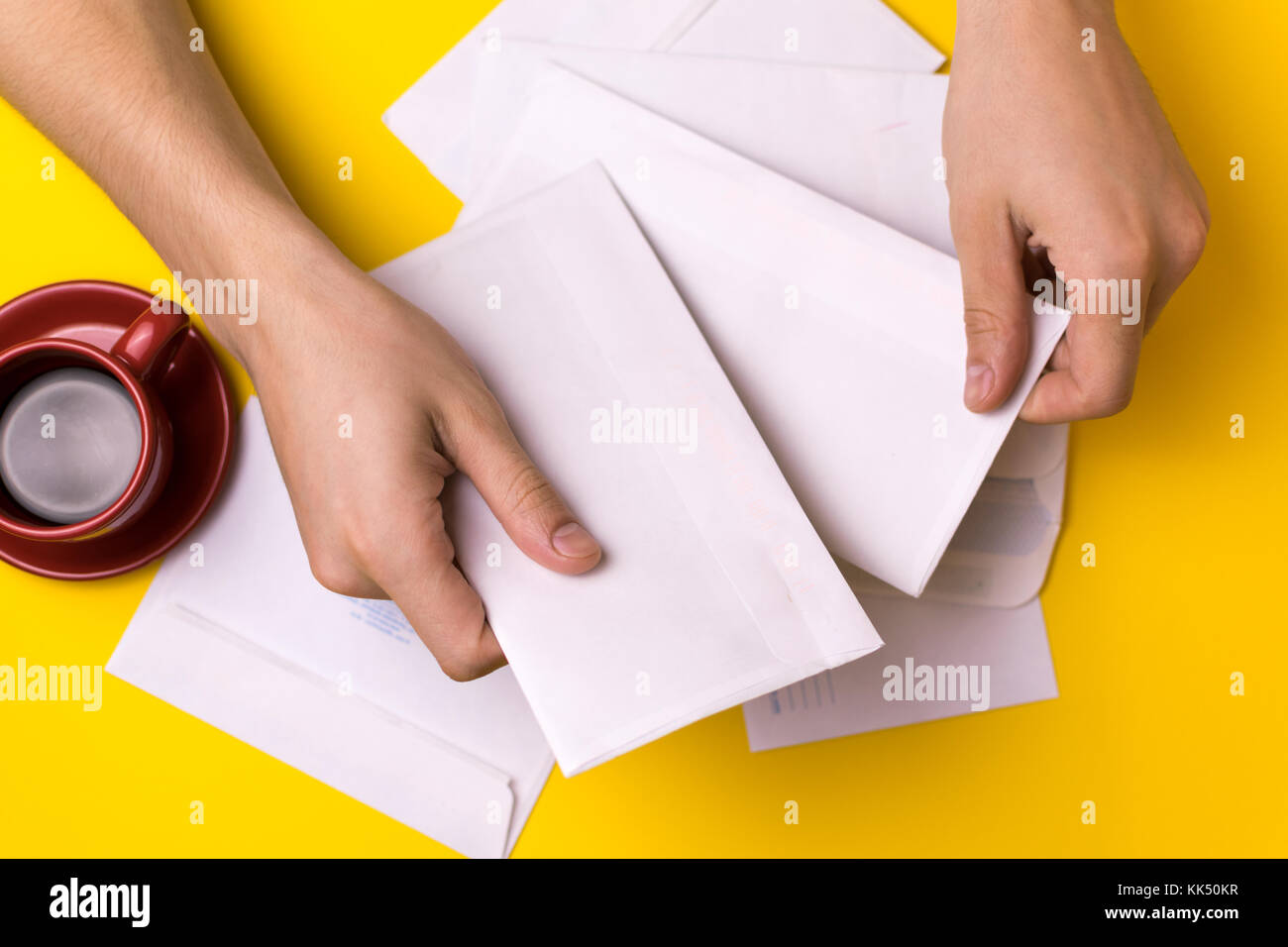 A man sorts the mail. Male hands the envelopes on a yellow background ...