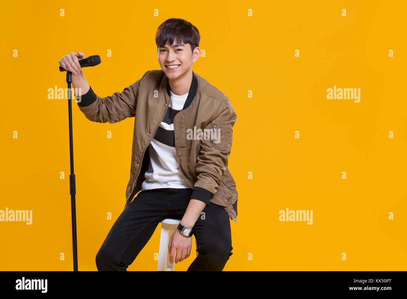Cheerful young Chinese man singing with microphone Stock Photo - Alamy