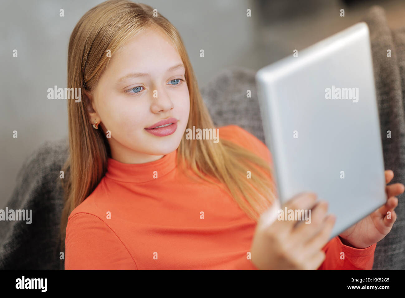 Positive mood. Pleasant cheerful delighted girl holding a tablet and ...