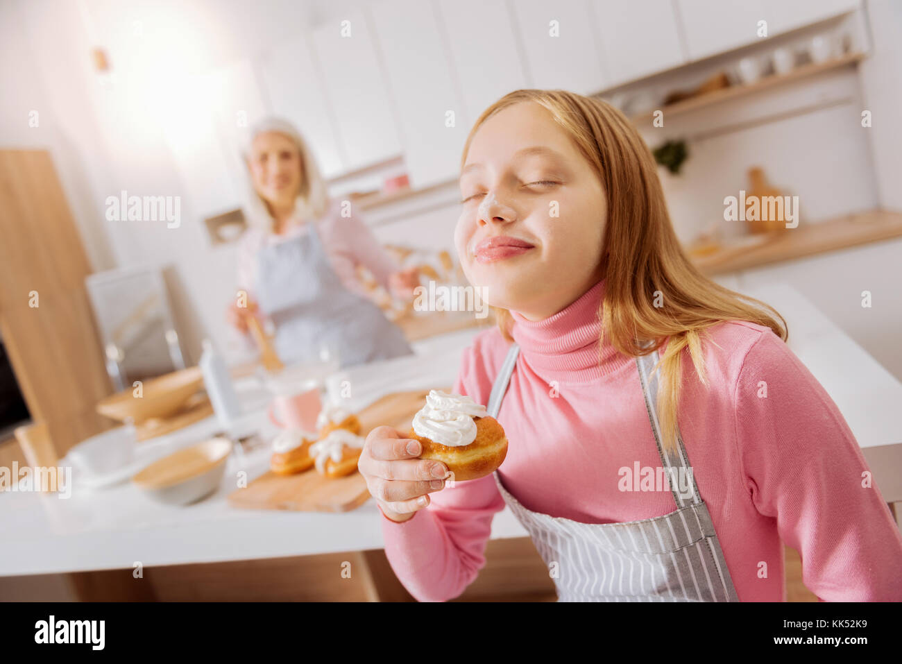 Best taste. Cute pleasant young girl holding a bun and closing her eyes ...