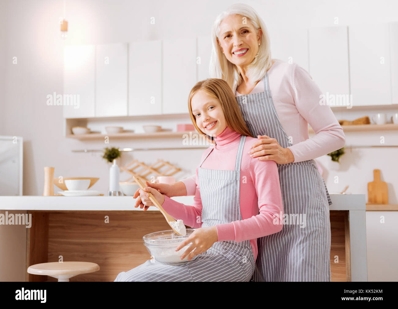 Young cook. Cheerful positive delighted girl sitting in the kitchen and ...