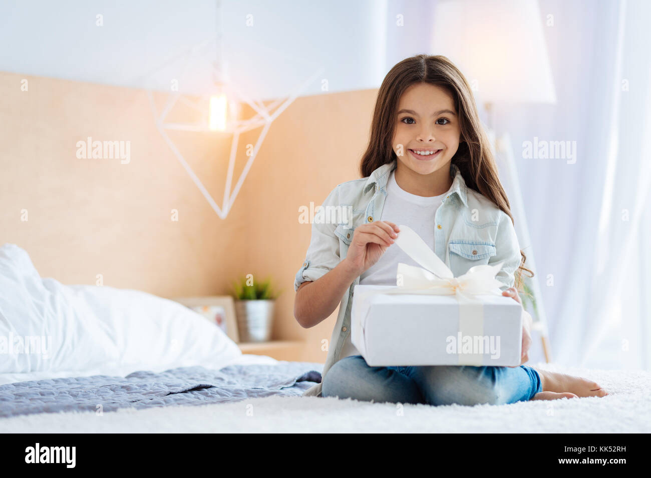 Open please. Jolly kind young girl unpack present while relaxing and ...