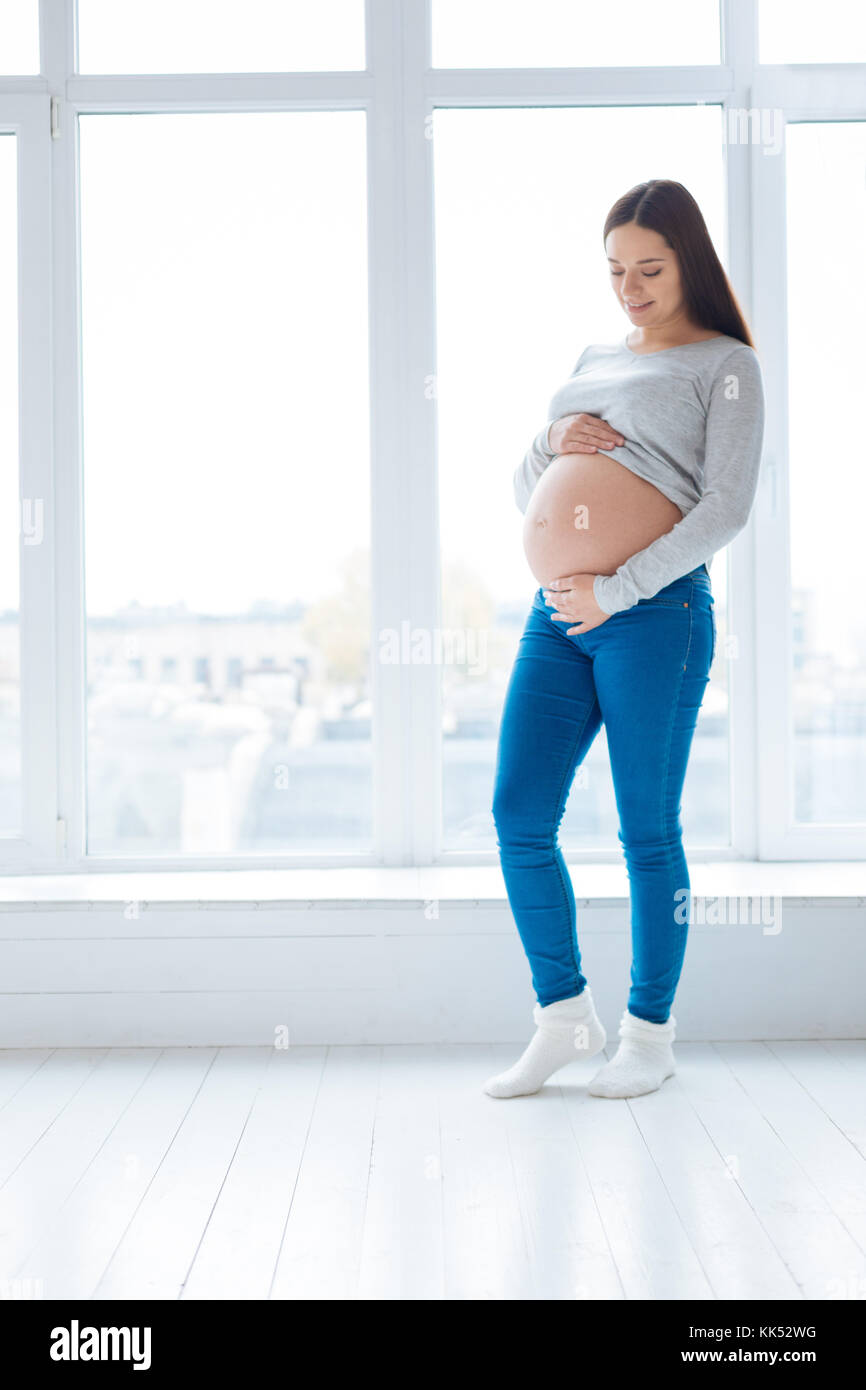My precious. Kind good looking pregnant woman looking at her belly ...