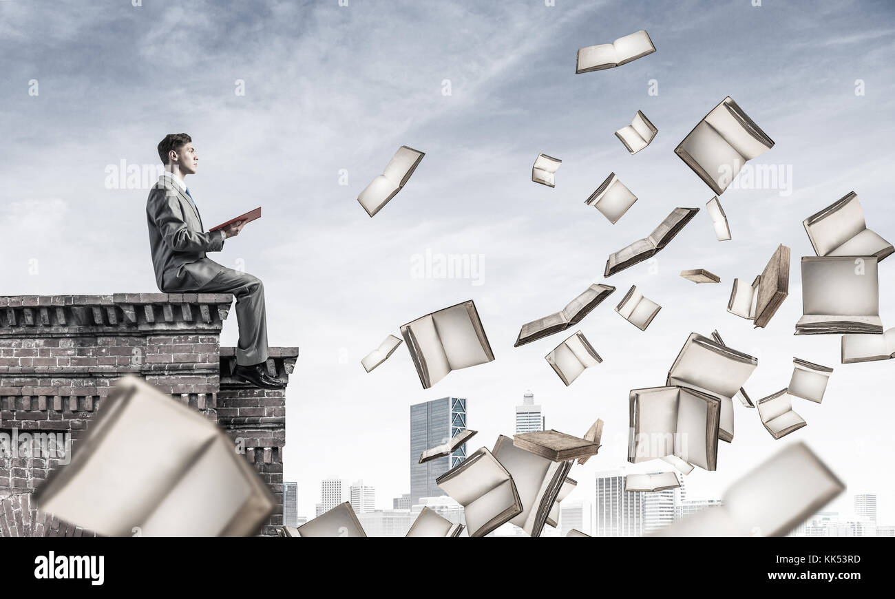 Man on roof reading book and many of them flying in air Stock Photo - Alamy