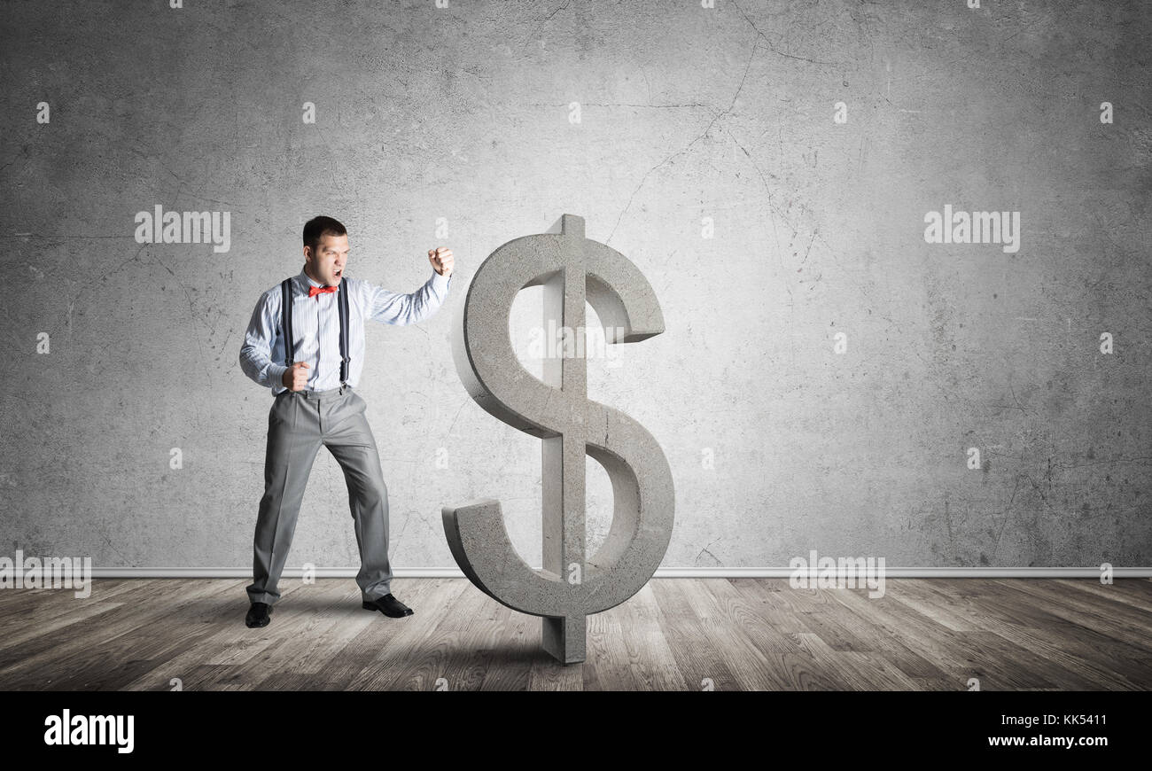 Determined banker man in empty concrete room breaking dollar figure ...