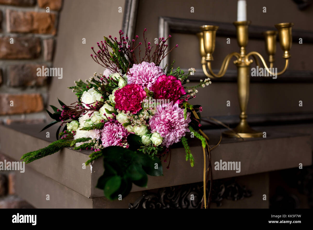 Brown decorative fireplace with colorful flower arrangement and candles ...