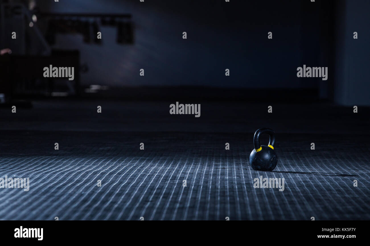 Close up view of a kettlebell on the floor in a dark gym with edgy ...
