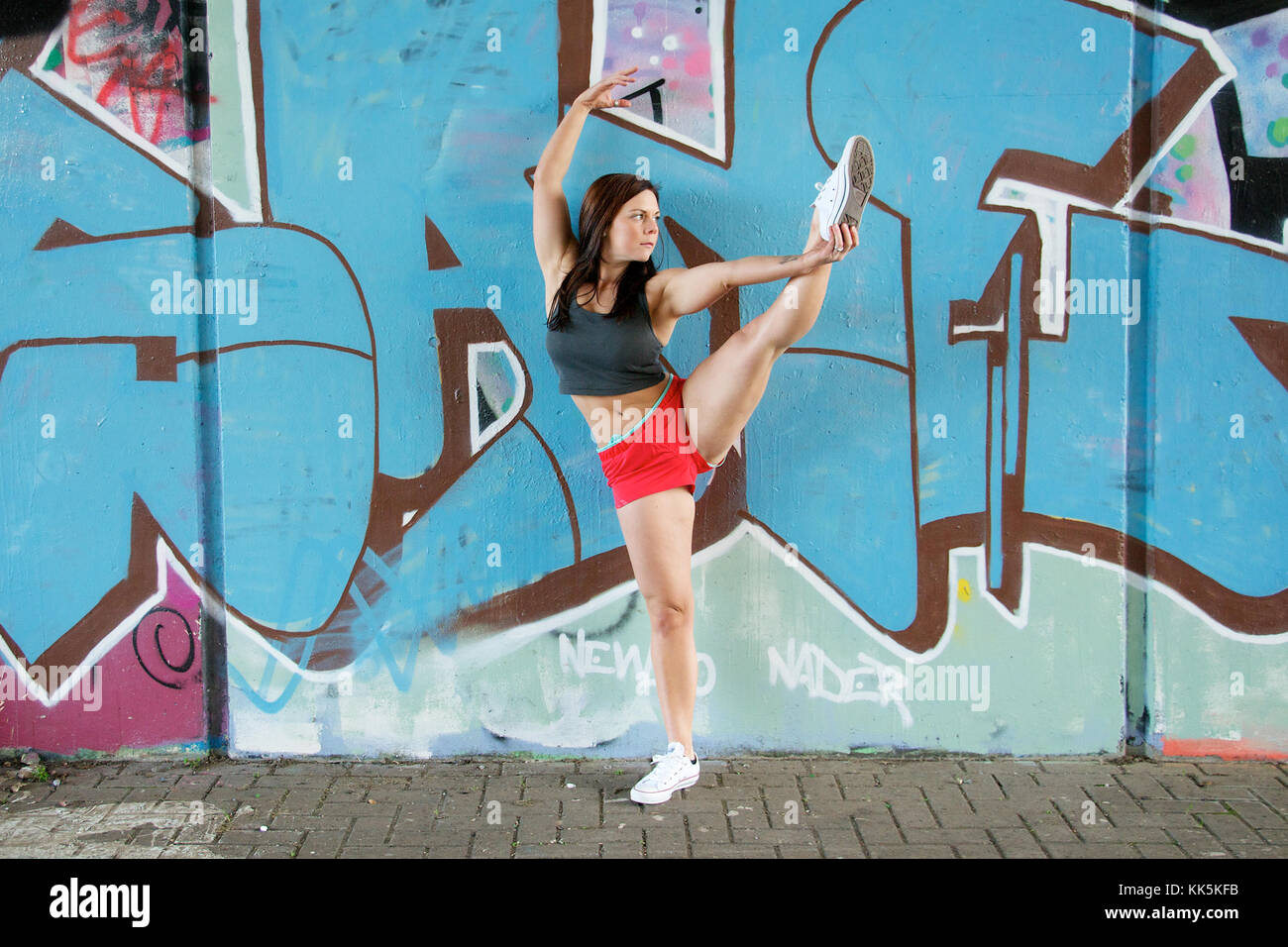 Girl doing exercises in anoutdoor location with a graffiti background ...
