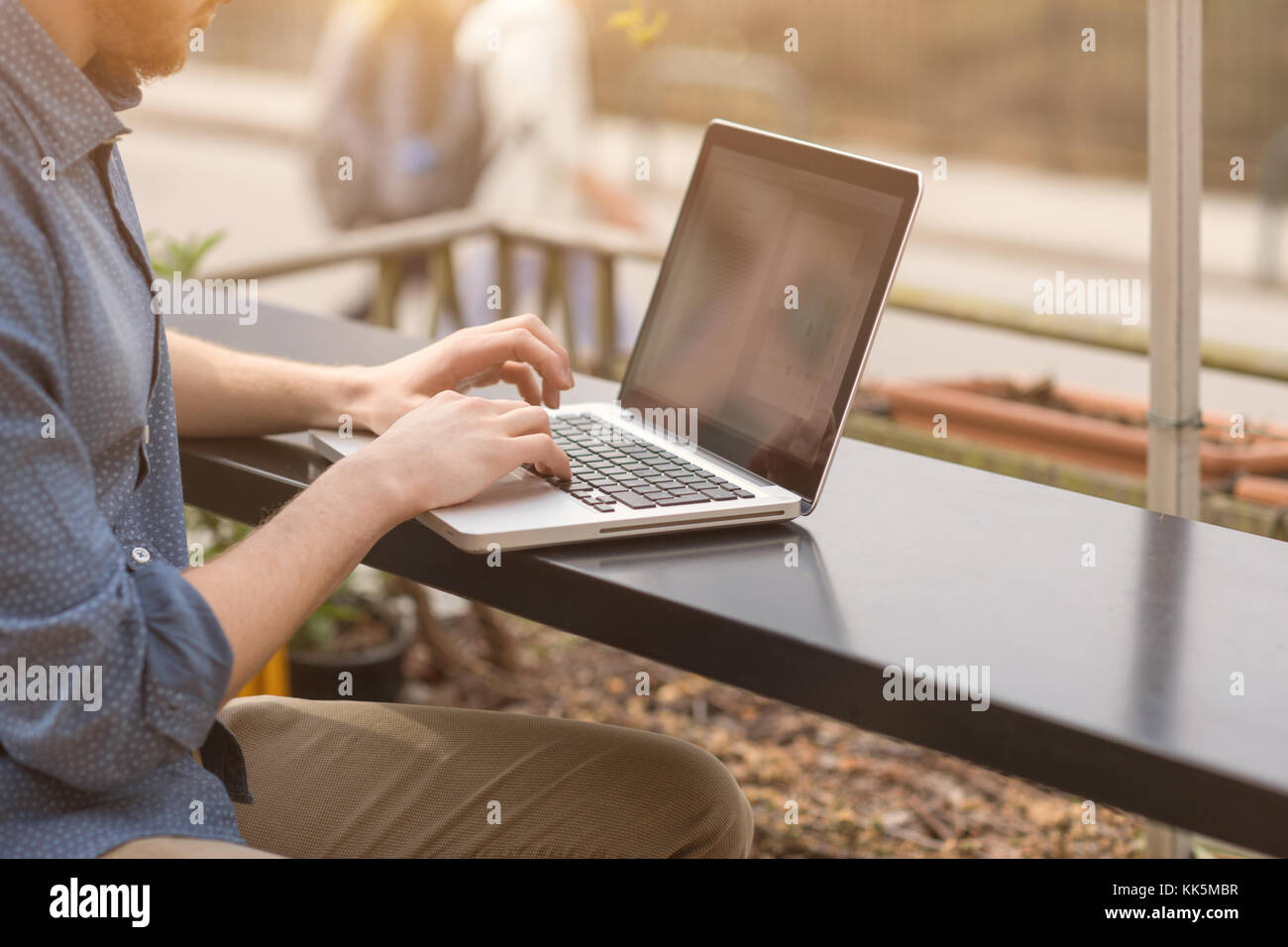 Unrecognizable man using a modern portable computer on an outdoor table ...