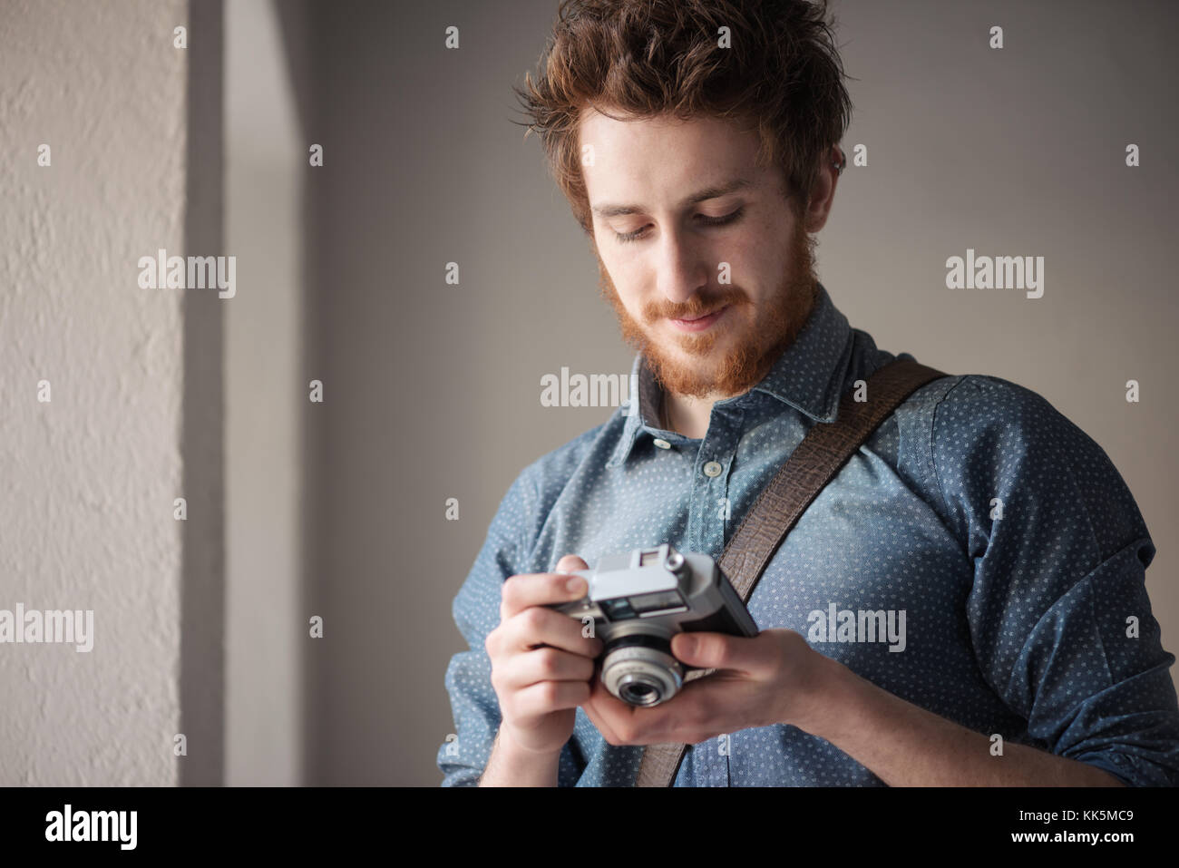 Hipster young man holding a vintage camera and checking settings Stock ...