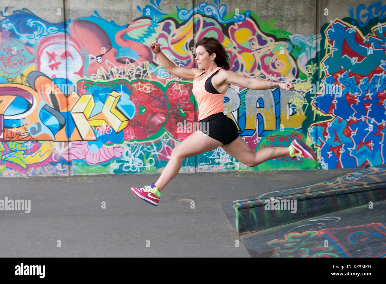 Girl doing exercises in anoutdoor location with a graffiti background ...