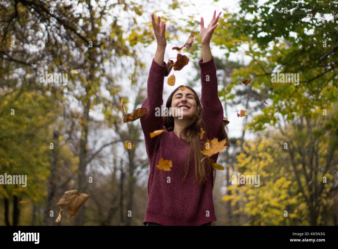 girl at a park thowing leaves in the air autumn scenery yellow leaf ...