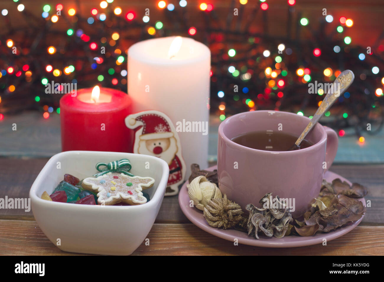 Festive still life with a cup of tea, bowl of candies and burning ...