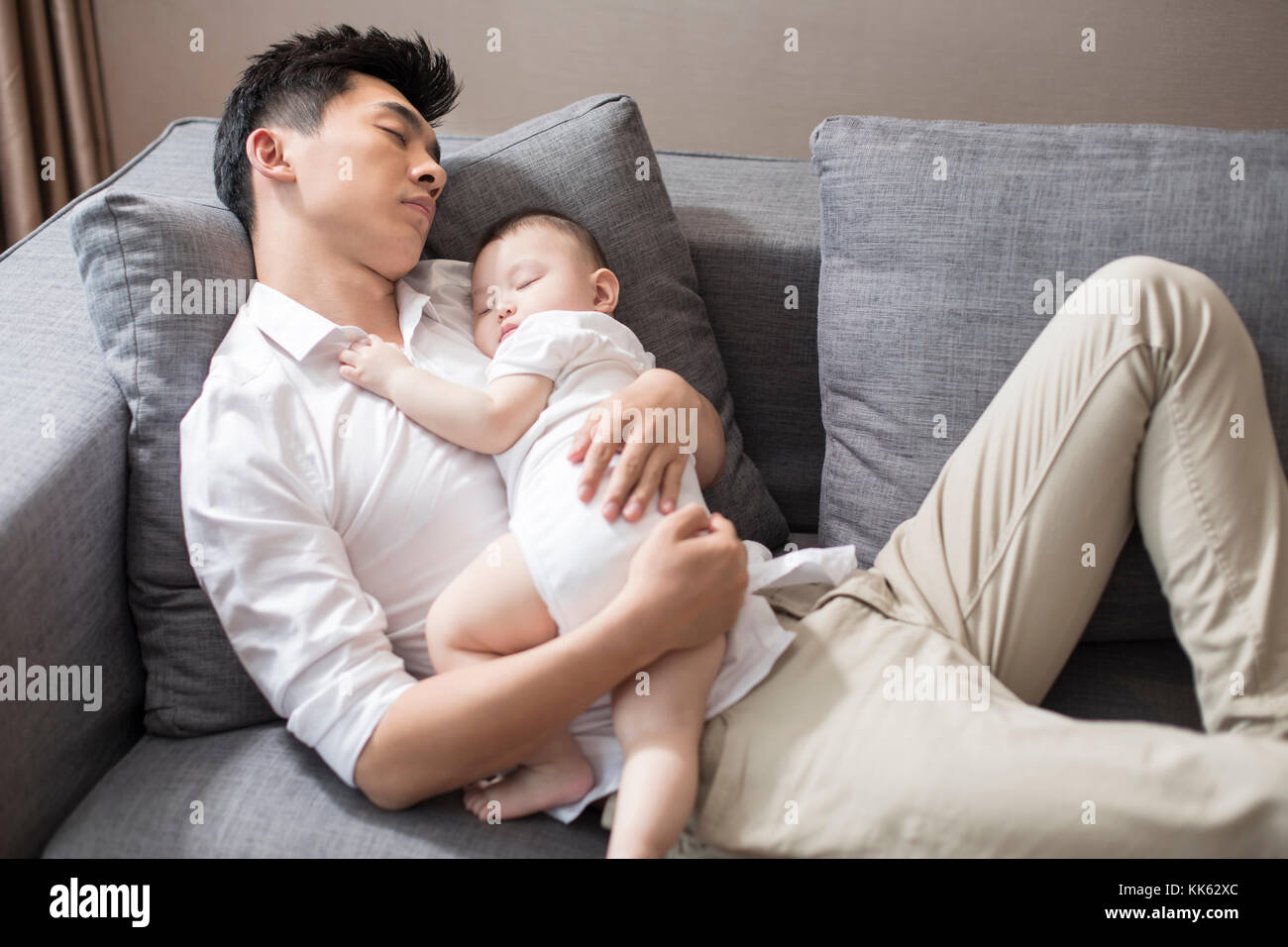 Young Chinese father and baby boy sleeping on sofa Stock Photo - Alamy