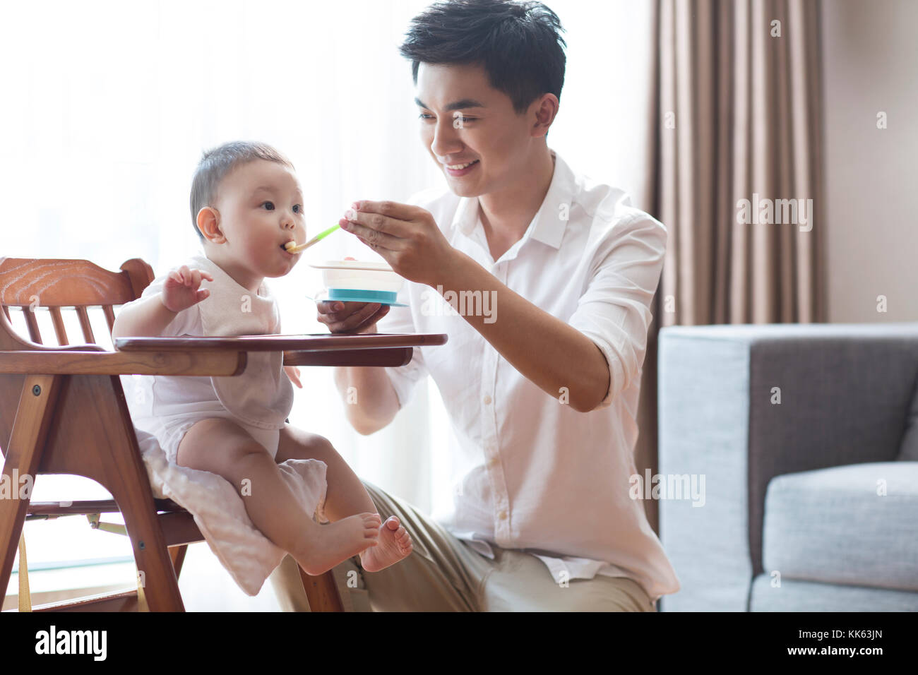 Young Chinese father feeding baby Stock Photo - Alamy