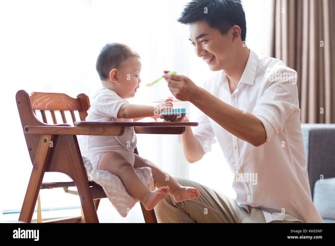Young Chinese father feeding baby Stock Photo - Alamy