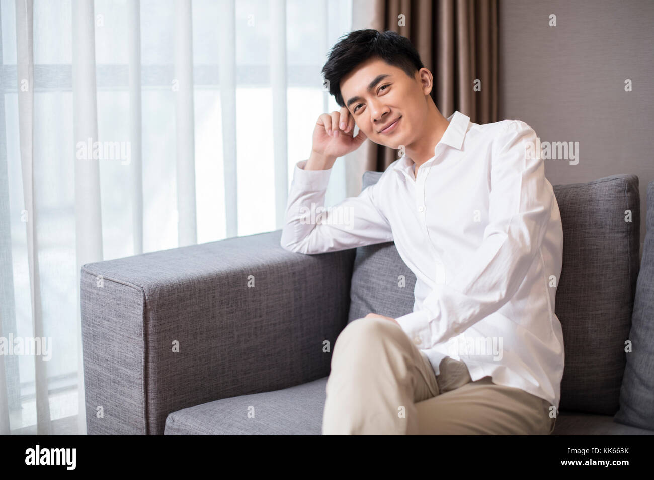 Young Chinese man relaxing on sofa Stock Photo - Alamy