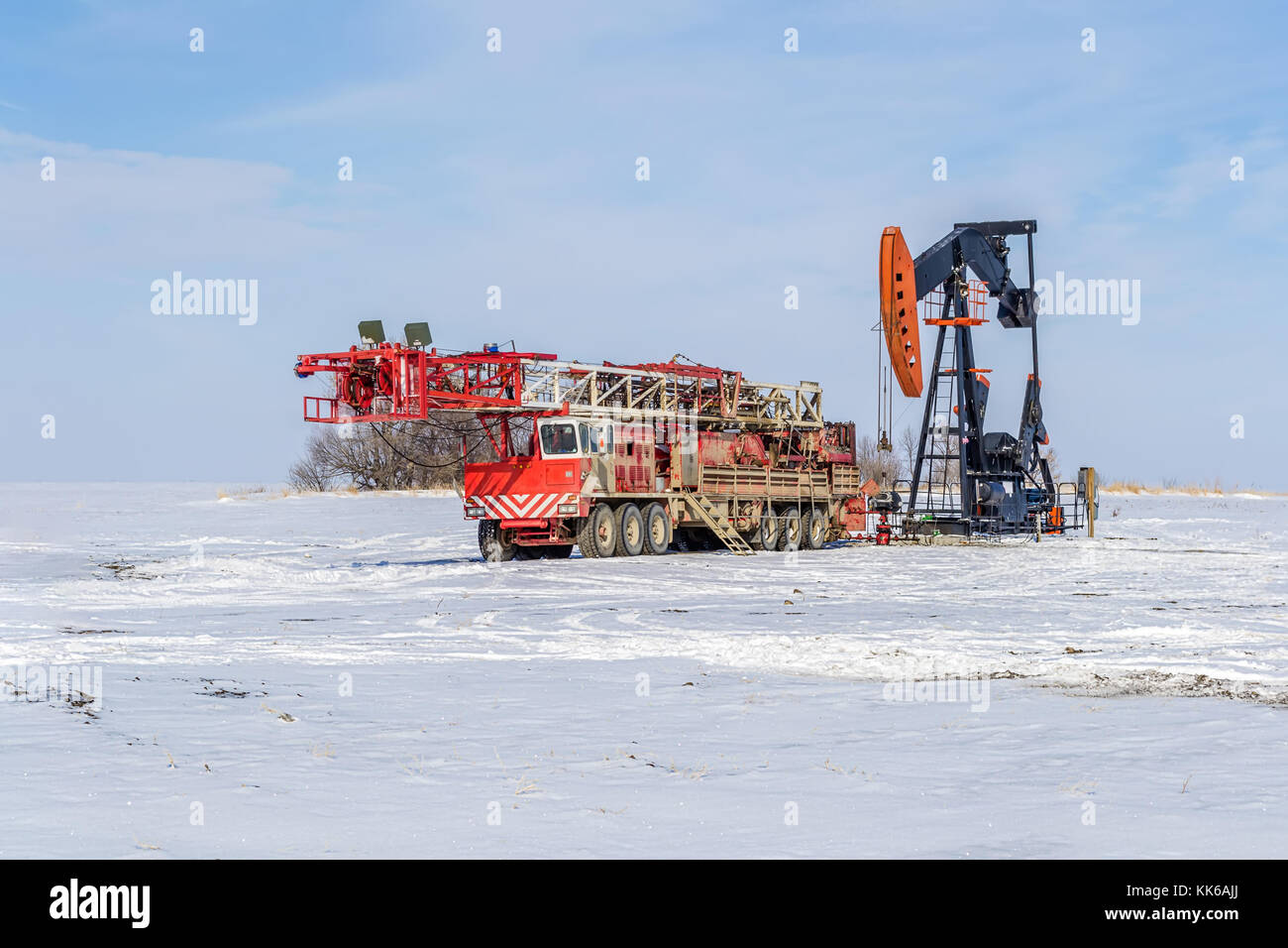 self-propelled red color drilling rig and pump jack in winter time on ...