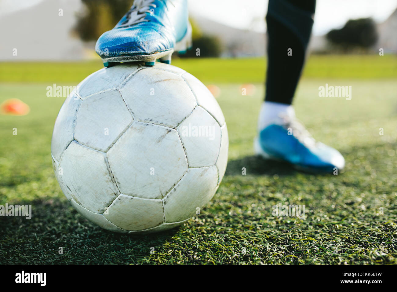 Close up of teenager's legs with a ball on football pitch. Cropped shot ...