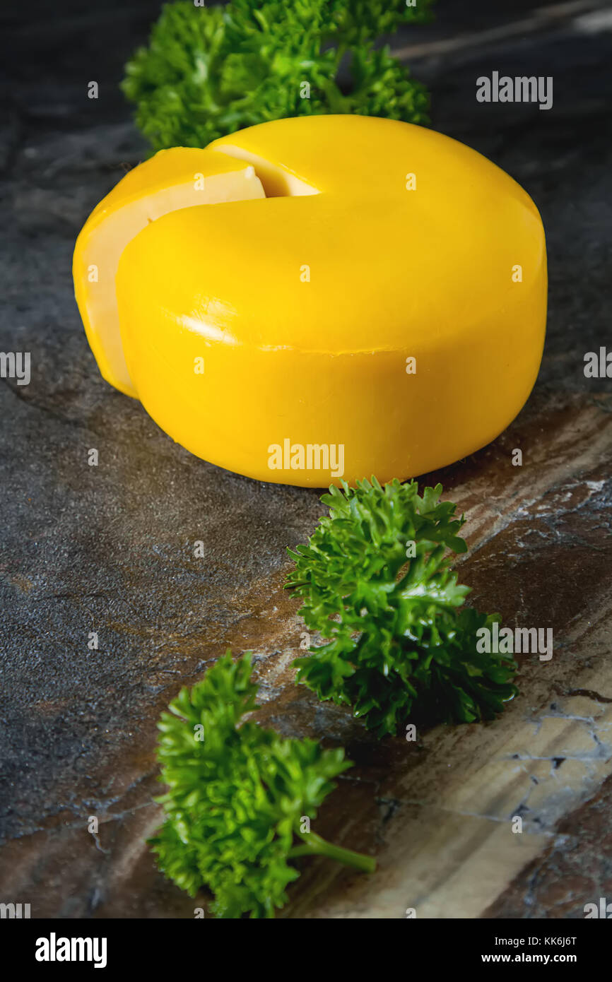 Round gouda cheese with parsley. Dark background Stock Photo - Alamy