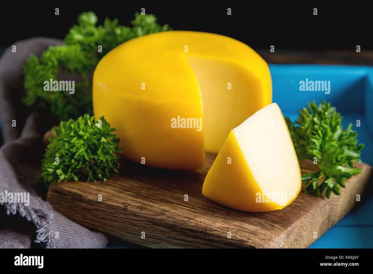 Round gouda cheese with parsley. Dark background Stock Photo - Alamy