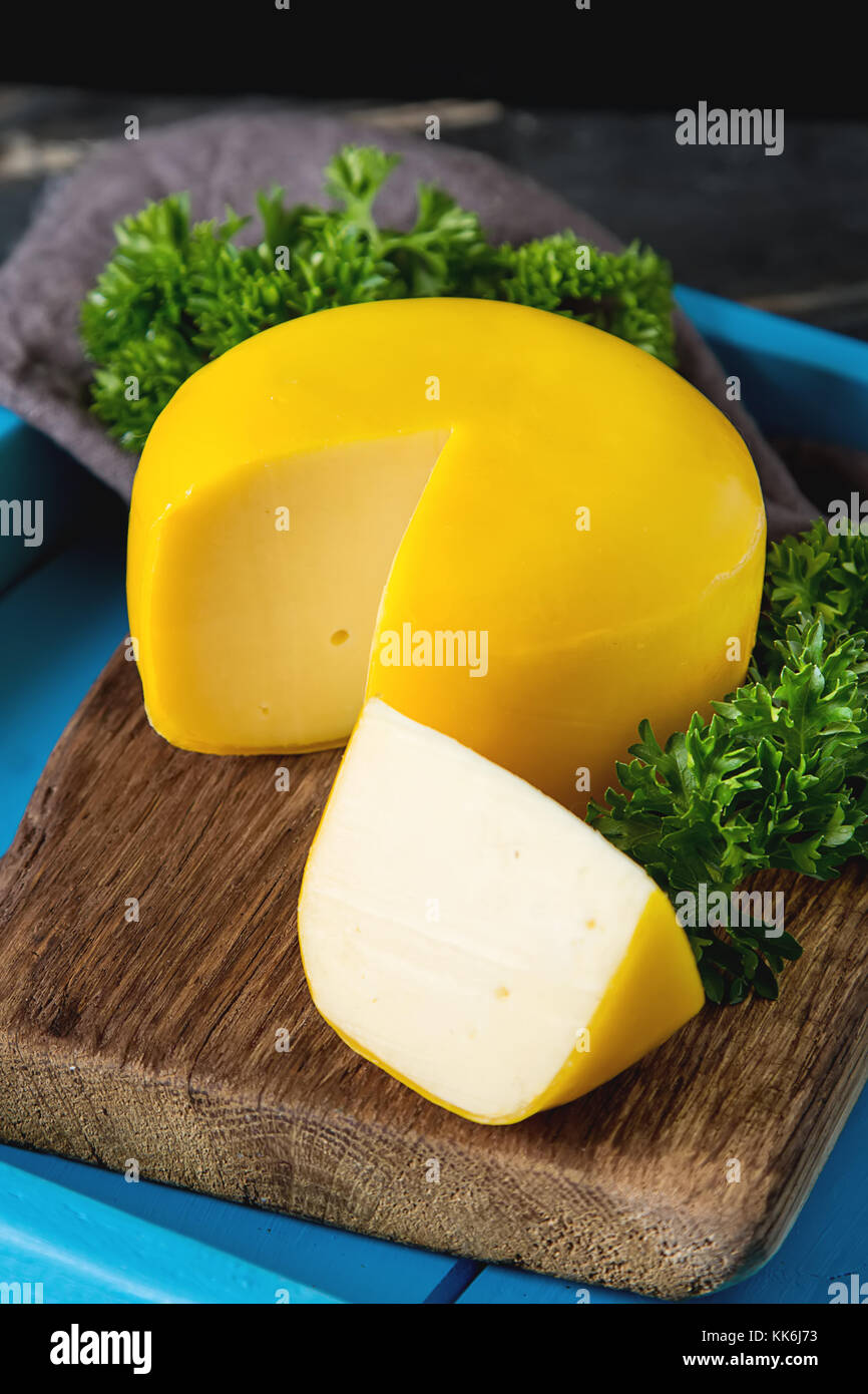 Round gouda cheese with parsley. Dark background Stock Photo - Alamy