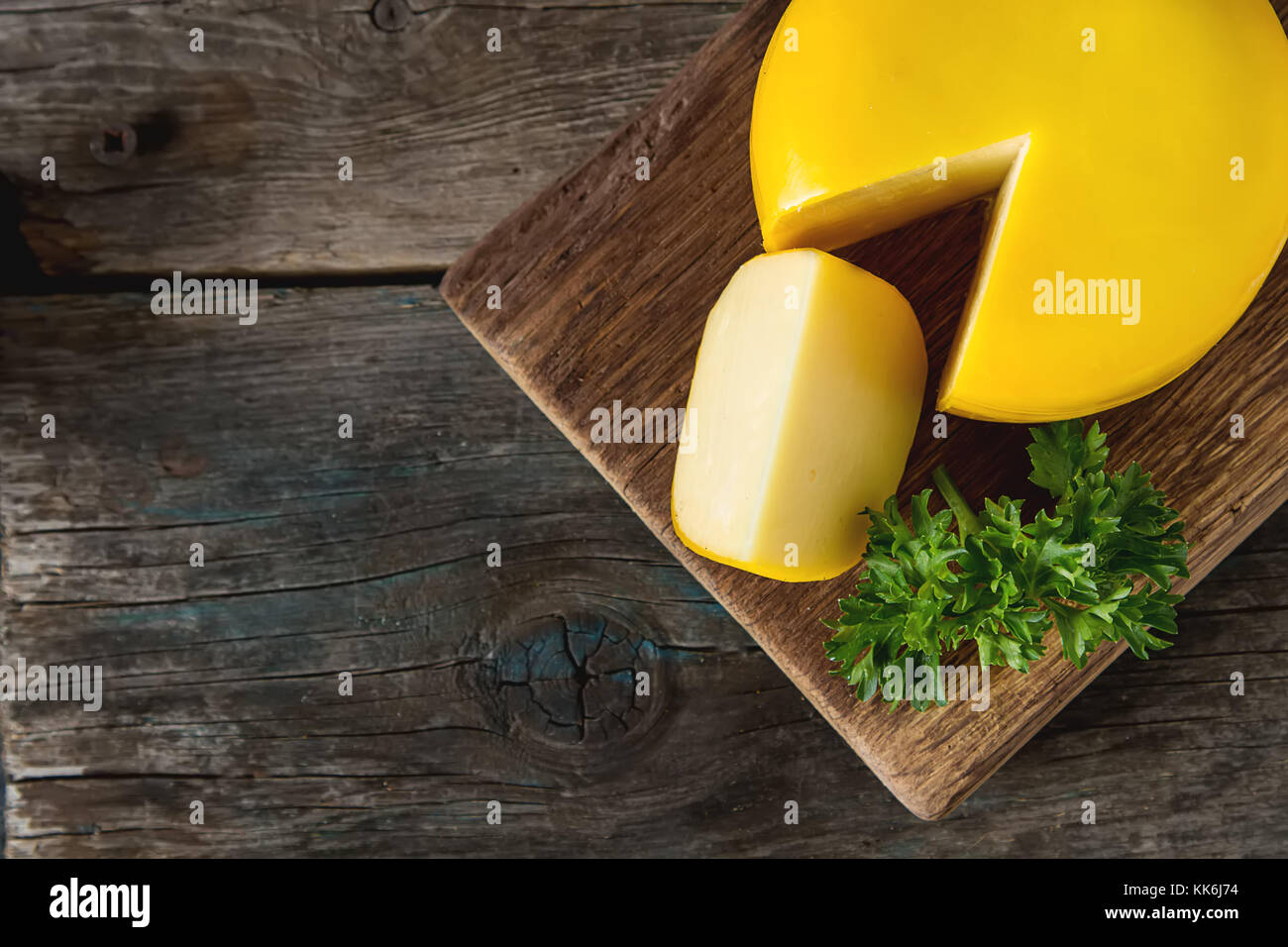 Round gouda cheese with parsley. Dark background Stock Photo - Alamy