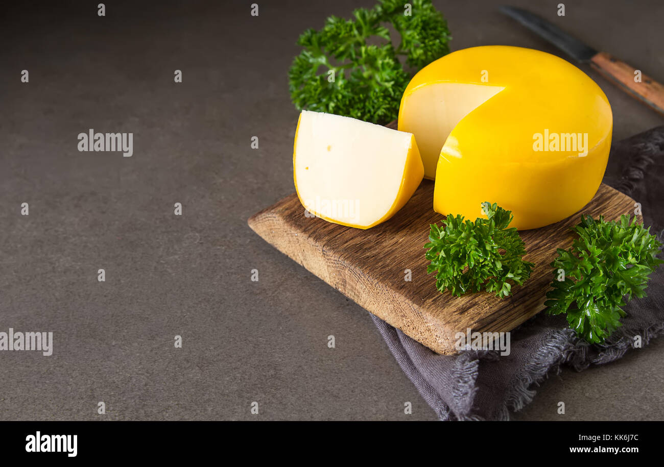 Round gouda cheese with parsley. Dark background Stock Photo - Alamy