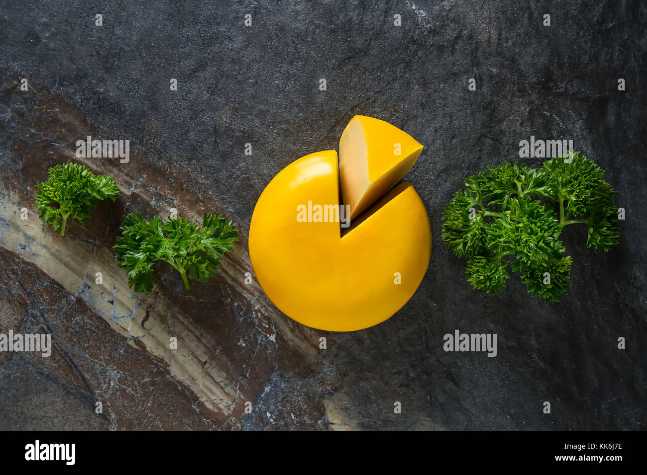 Round gouda cheese with parsley. Dark background Stock Photo - Alamy