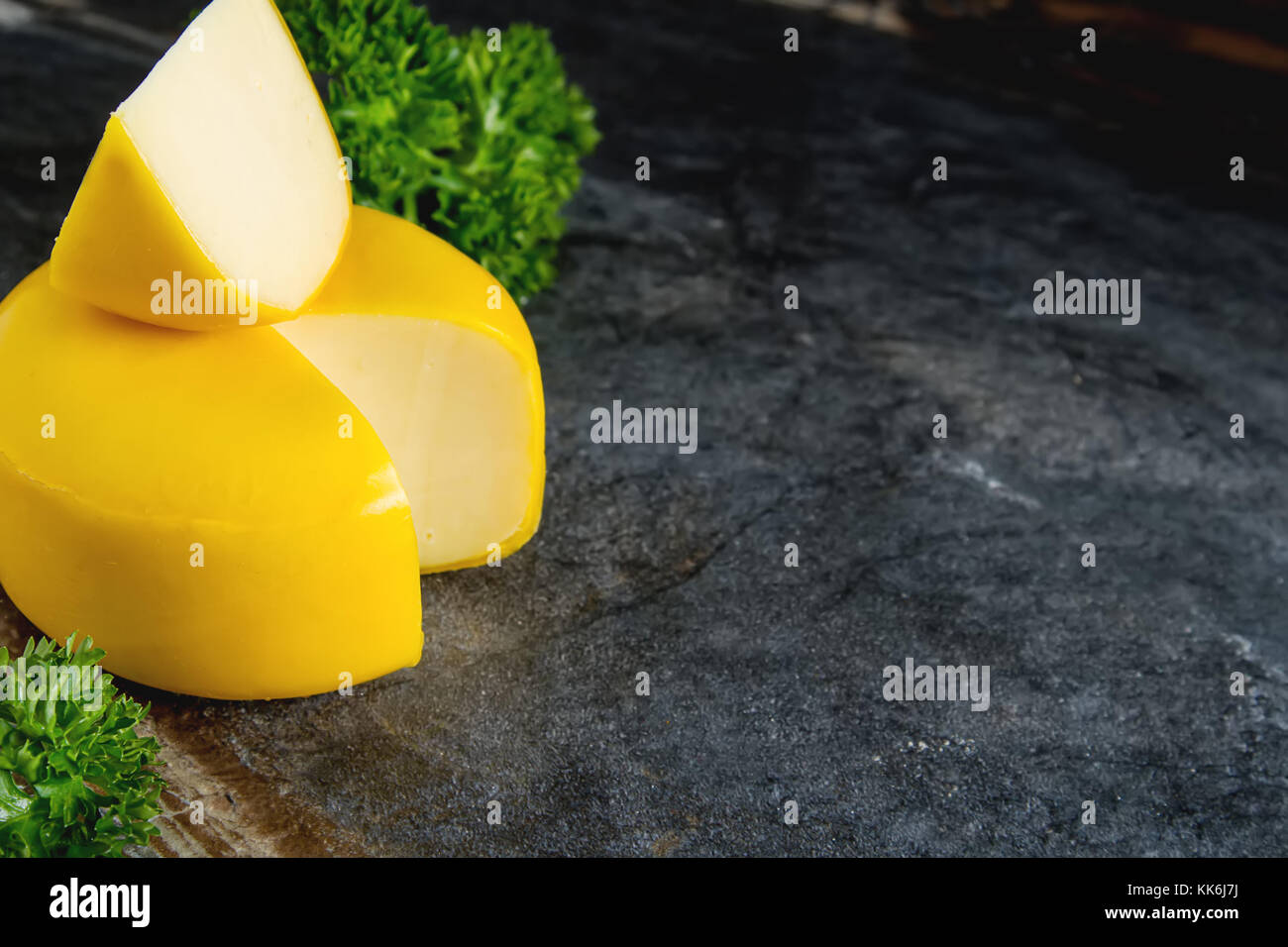 Round gouda cheese with parsley. Dark background Stock Photo - Alamy