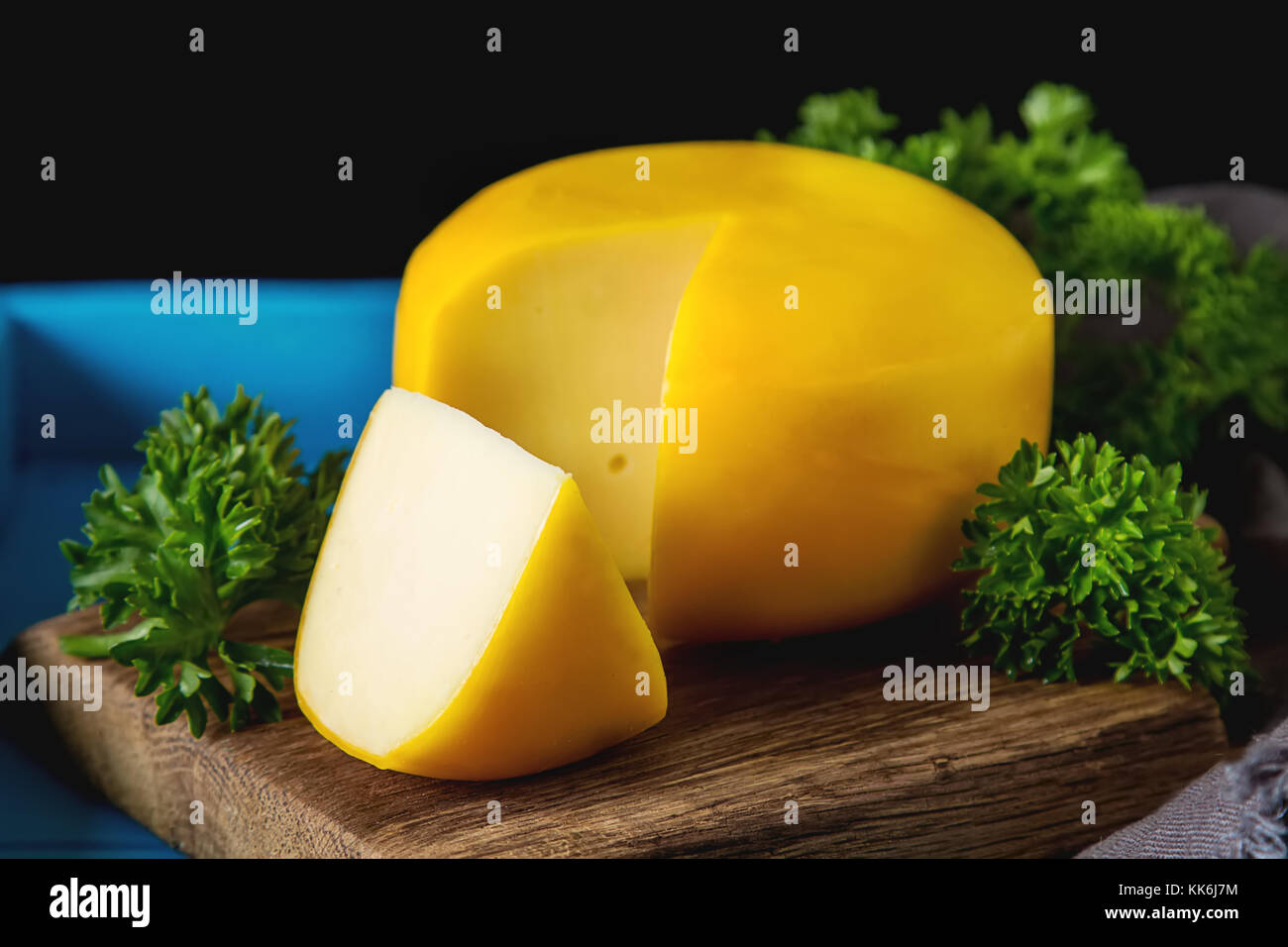 Round gouda cheese with parsley. Dark background Stock Photo - Alamy