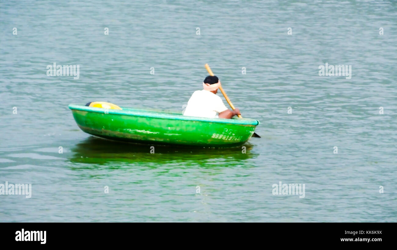 Man sailing a small boat in the water reservoir to catch fish in the ...