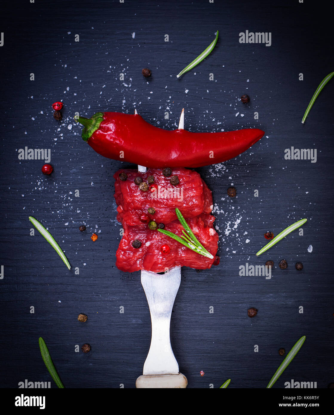 two pieces of beef and red chili pepper strung on a kitchen plug on a ...