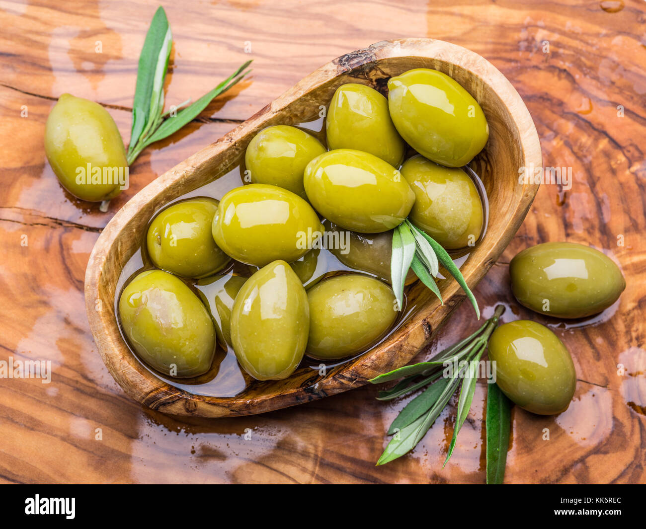 Whole table olives in the wooden bowl on the table. Top view Stock ...