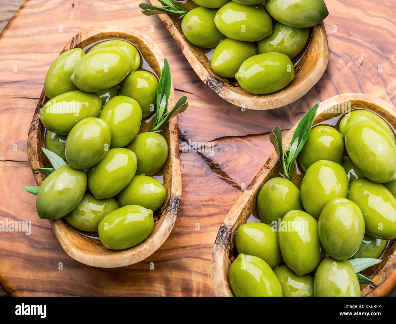 Whole table olives in the wooden bowl on the table. Top view Stock ...
